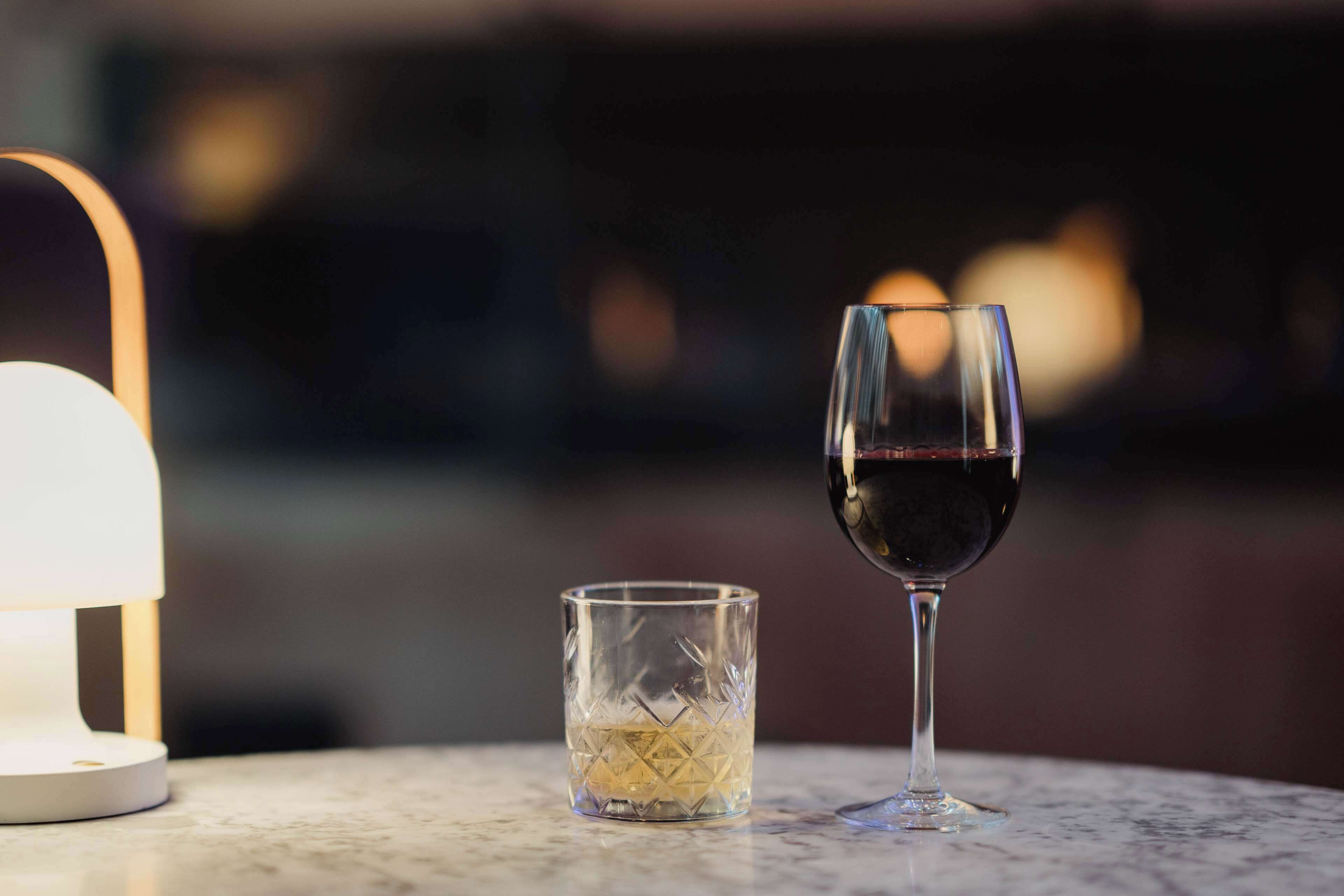 Um copo de vinho tinto e um pequeno copo com bebida sobre uma superfície de mármore.