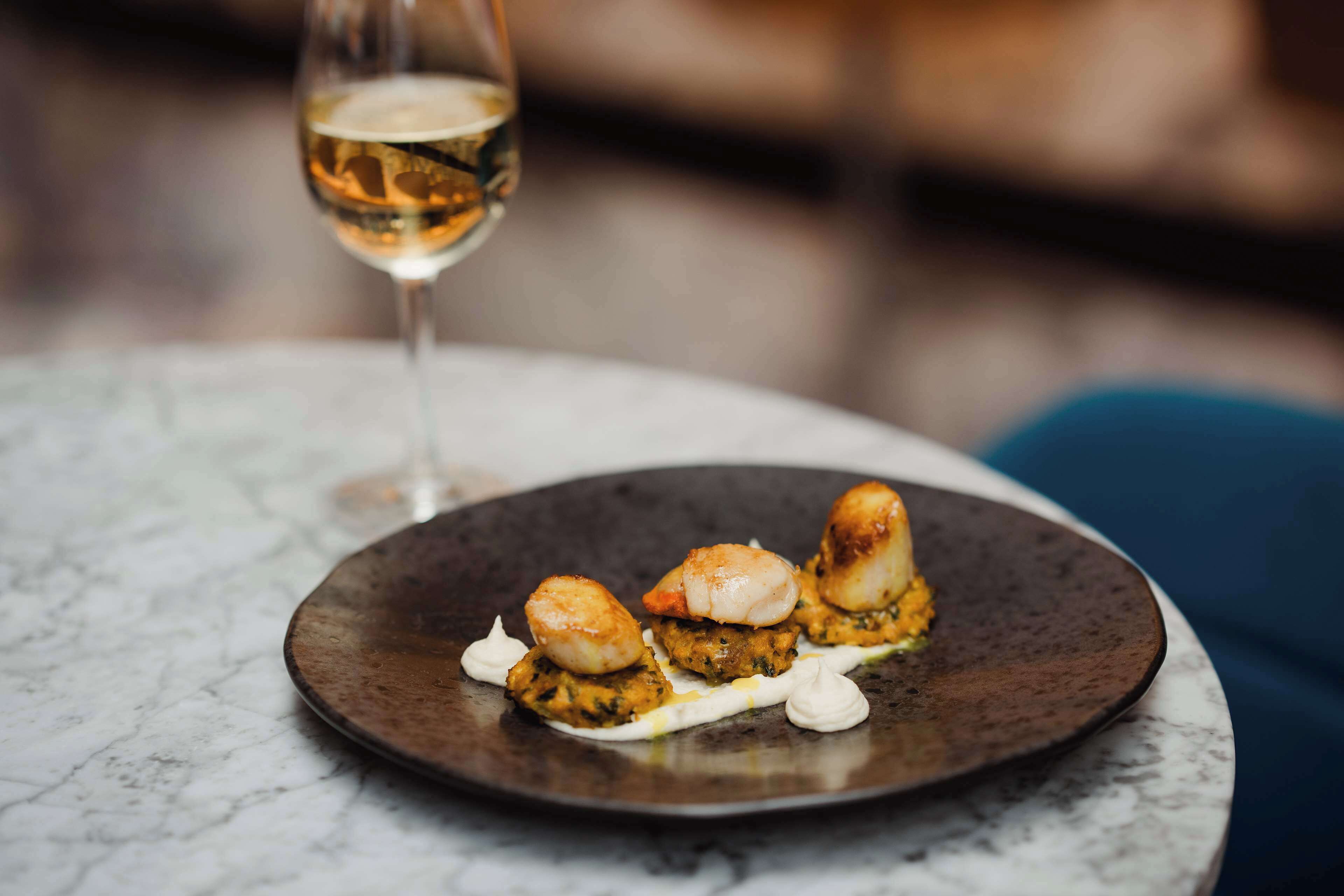 Um prato com comida e um copo de vinho sobre uma mesa de mármore.