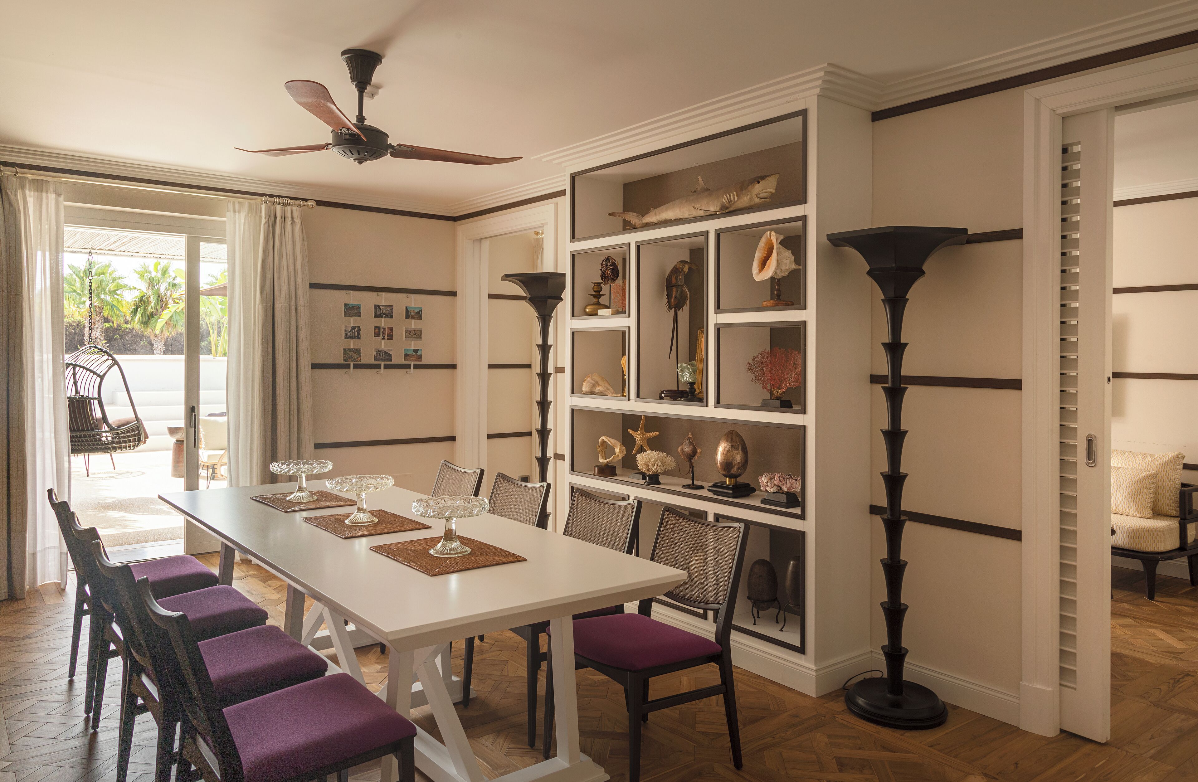 Uma sala de jantar com uma mesa comprida, cadeiras e um ventilador de teto.