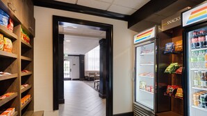 Um corredor com prateleiras de lanches e uma vitrine refrigerada.
