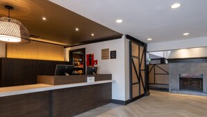 Uma área de recepção com balcão de madeira, lareira e piso em padrão herringbone.