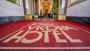 Tapete vermelho que conduz ao Hotel Royal Victoria, com padrão de piso xadrez.