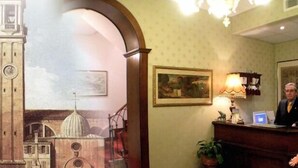 Um saguão de hotel com um grande mural de um horizonte urbano, uma mesa de recepção e um quadro emoldurado na parede.