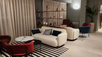 Uma sala de estar moderna com um sofá branco, cadeiras vermelhas, uma mesa redonda pequena e um tapete listrado.