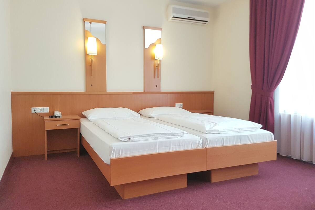 Uma cama de casal com cabeceira de madeira, mesa de cabeceira, espelho e ar condicionado.