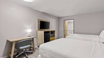 Quarto de hotel com cama, escrivaninha com cadeira, televisão e micro-ondas.