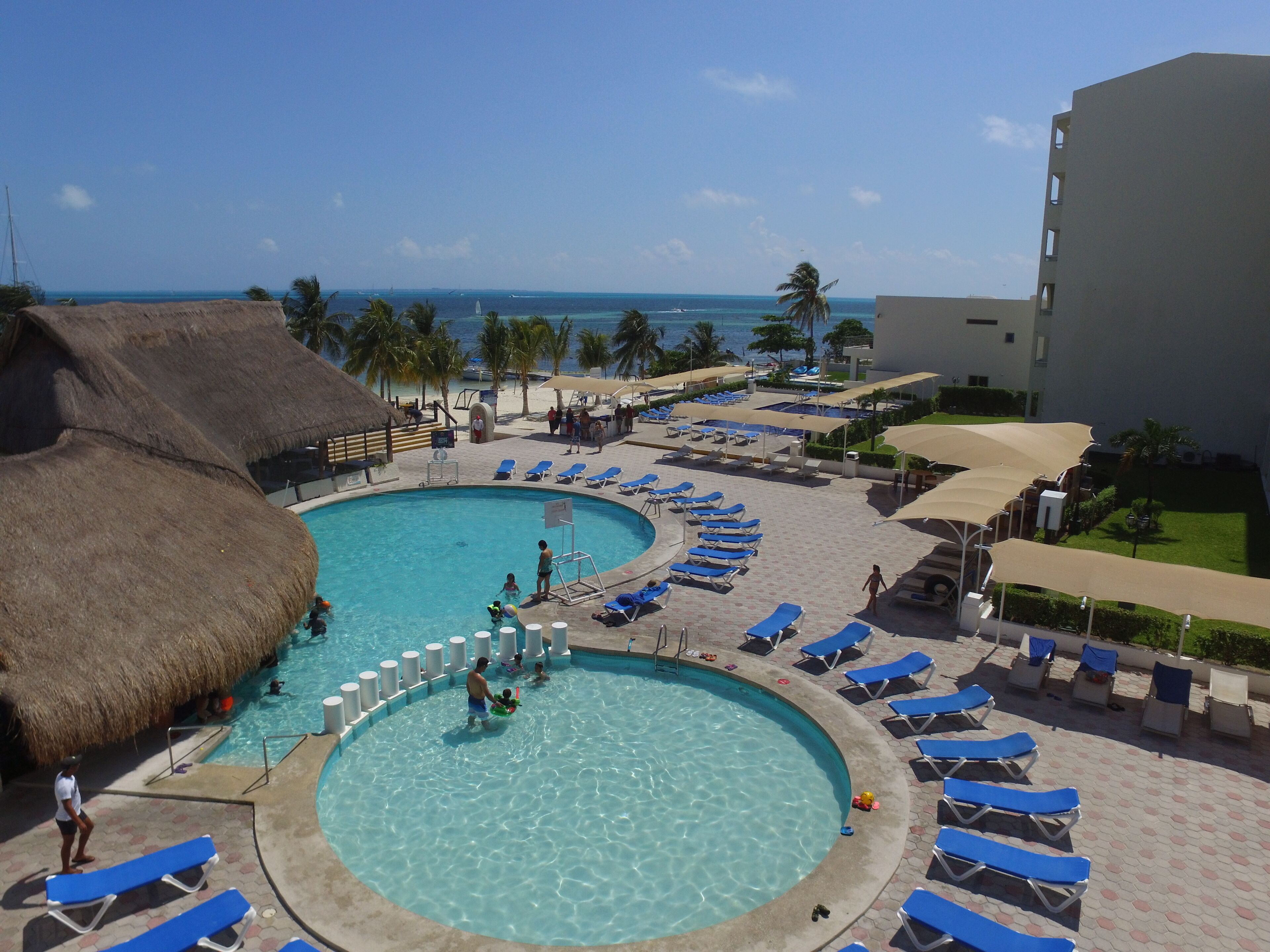 Área de piscina do resort com piscina circular, espreguiçadeiras e vista para o mar.