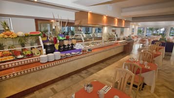 Uma área de buffet com diversos tipos de comida e um espaço de estar com mesas e cadeiras.