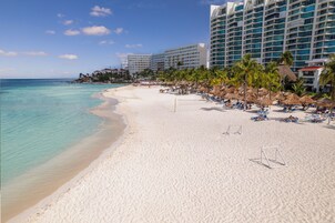 Praia particular, areia branca, espreguiçadeiras, guarda-sóis 