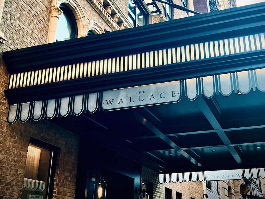 Entrada de um prédio com letreiro luminoso que diz 'The Wallace'.