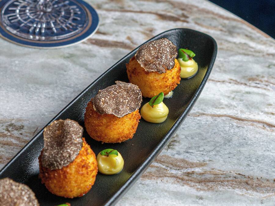 Um prato de sobremesa com trufas e uma taça de martini sobre uma mesa de mármore.