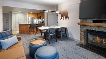 Uma sala de estar moderna com lareira, uma área de refeições com cadeiras e uma cozinha ao fundo.