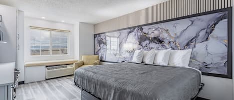 Quarto moderno com cama grande, janela com vista e painel de arte em mármore.