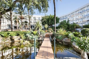 Um hotel com piscina, rodeado por plantas tropicais e palmeiras.