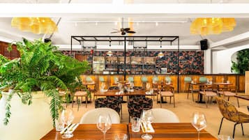 Um restaurante com mesas e cadeiras de madeira e um espaço de bar com prateleiras cheias de garrafas.