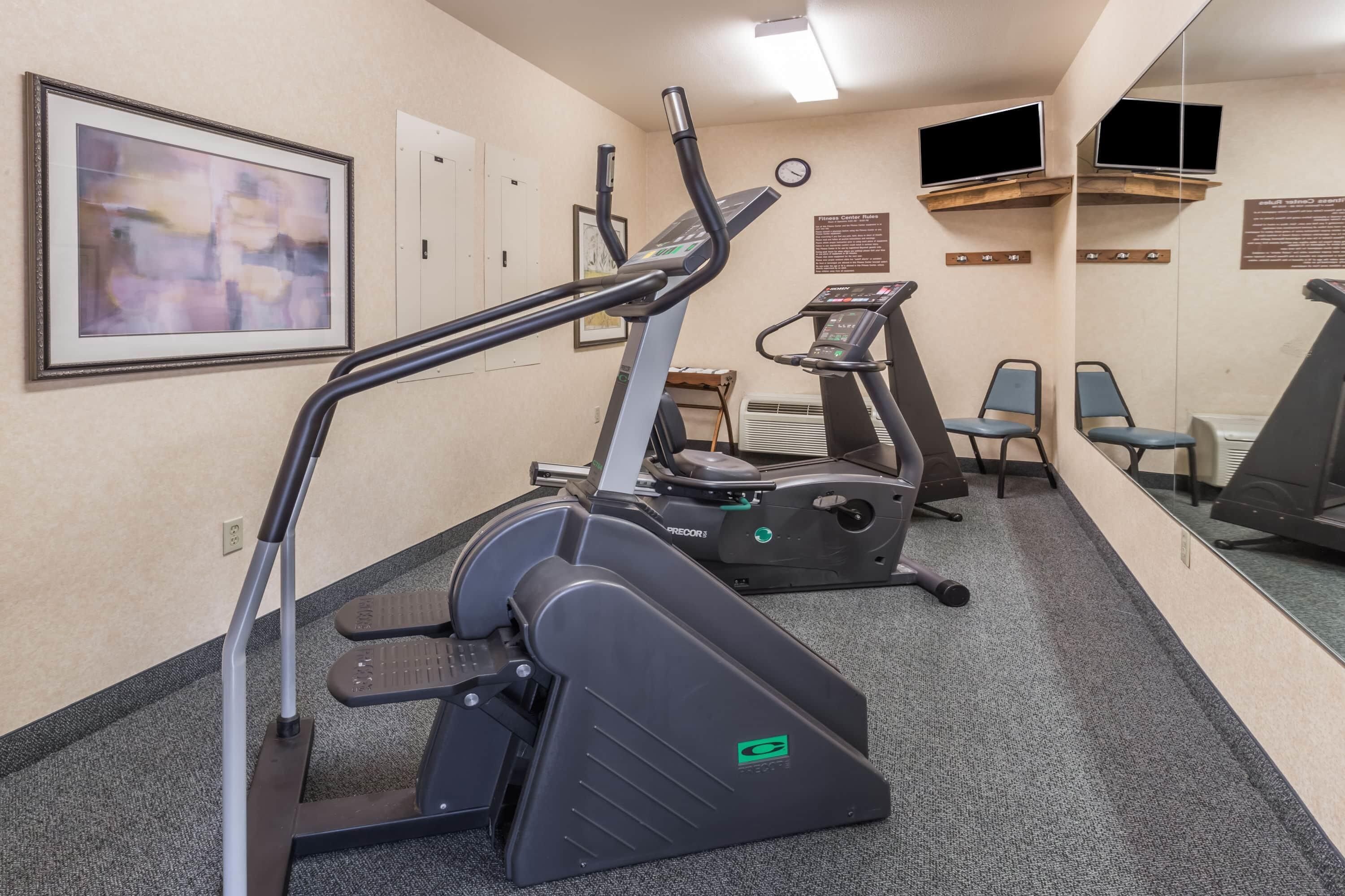 Centro de fitness com esteiras, bicicletas ergométricas e um espelho.