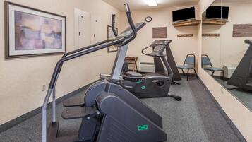 Centro de fitness com esteiras, bicicletas ergométricas e um espelho.