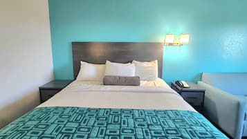 Cama bem arrumada com colcha estampada, cabeceira escura e duas luminárias de mesa.