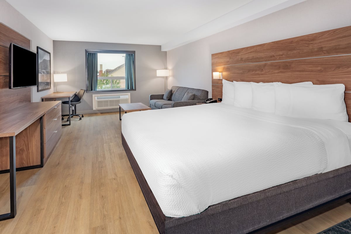 Quarto de hotel moderno com uma cama grande, uma mesa de trabalho, uma cadeira e uma televisão.