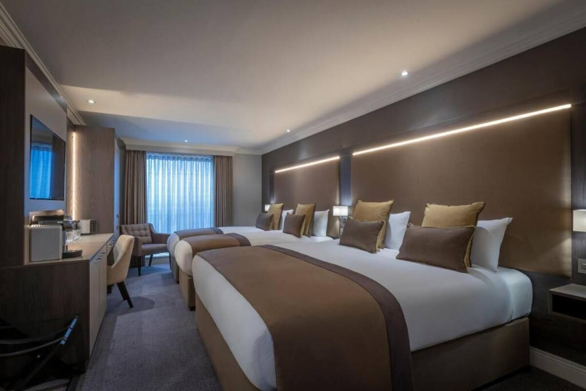 Quarto de hotel com uma cama grande, uma escrivaninha e uma cadeira.