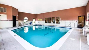 Uma piscina interior com águas cristalinas azuis, rodeada por pisos e paredes revestidos de azulejos brancos.