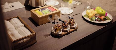 Mesa de café da manhã bem organizada com cafeteira, bule de chá e diversos alimentos, incluindo frutas e nozes.