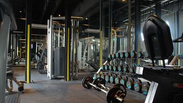 Uma academia com equipamentos de musculação, aparelhos de ginástica e halteres.