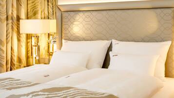 Quarto de hotel com uma cama grande, duas mesas de cabeceira, uma luminária e uma cabeceira estampada.