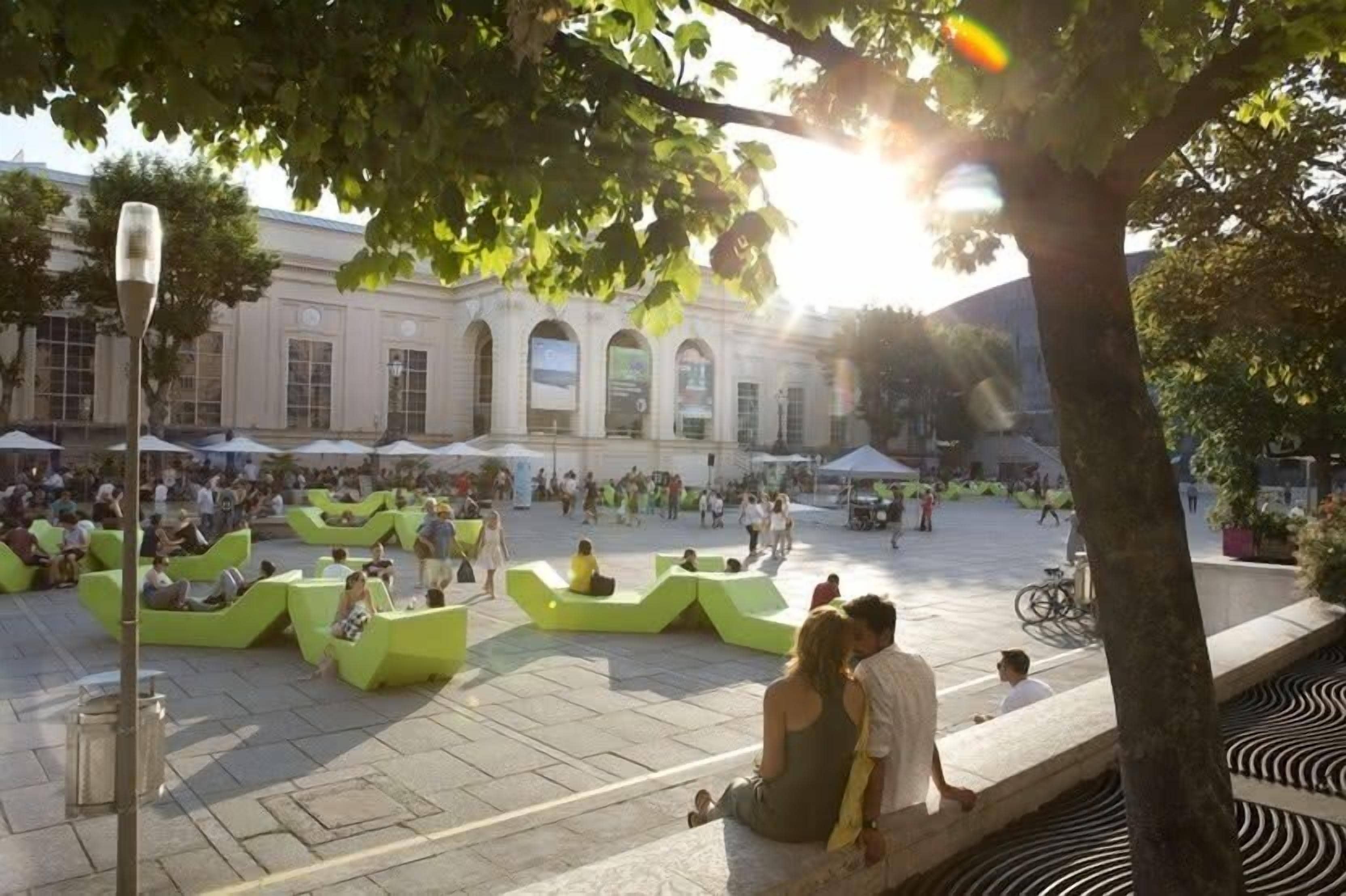 Uma praça pública ao ar livre com áreas de estar e um edifício ao fundo.