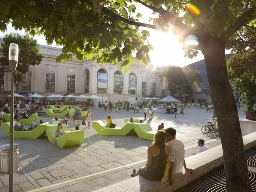 Uma praça pública ao ar livre com áreas de estar e um edifício ao fundo.