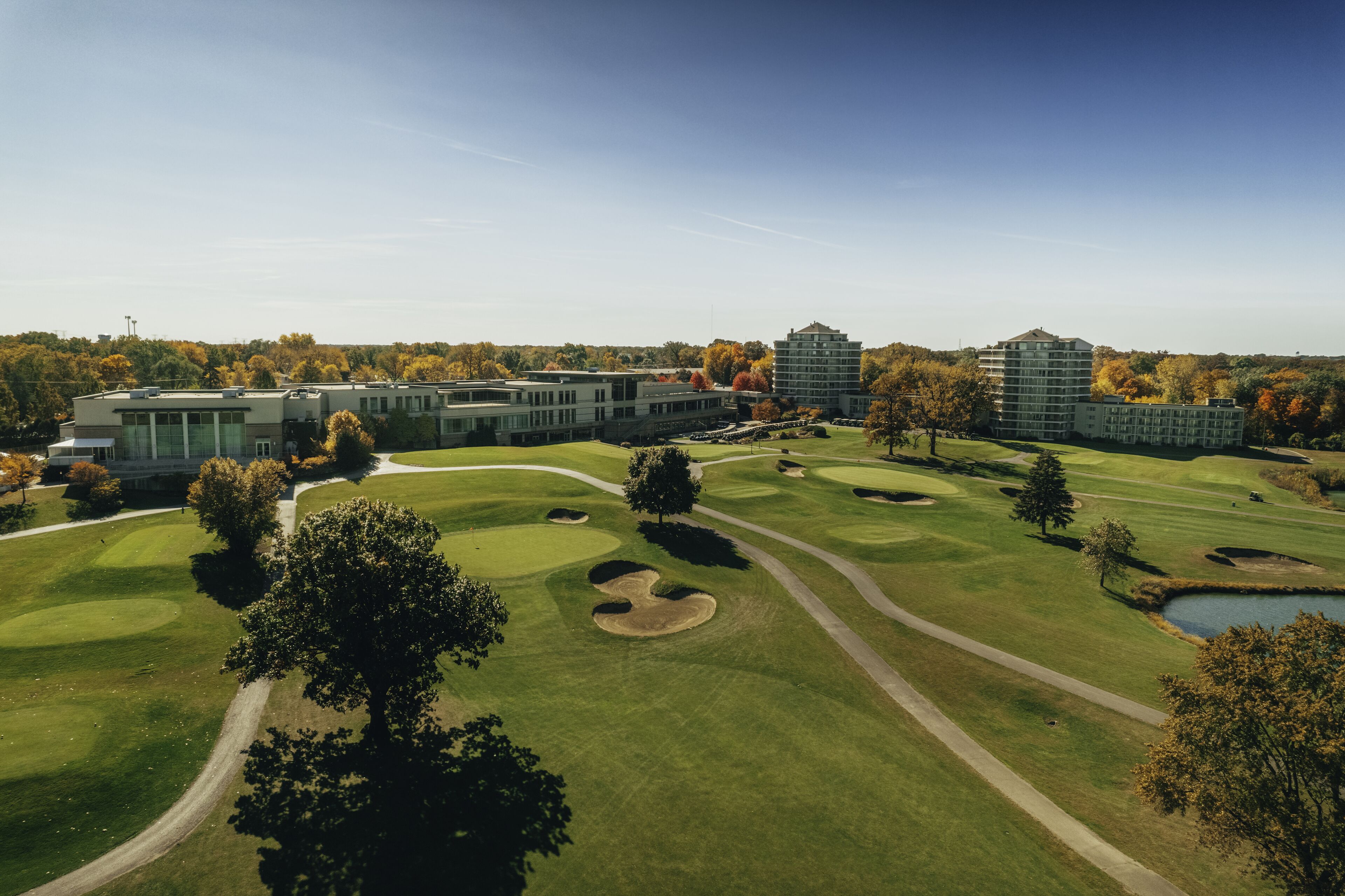 Um campo de golfe com um clube e edifícios residenciais ao fundo.