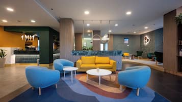 Um hall moderno com balcão de recepção, área de estar com sofás e cadeiras, e um bar.