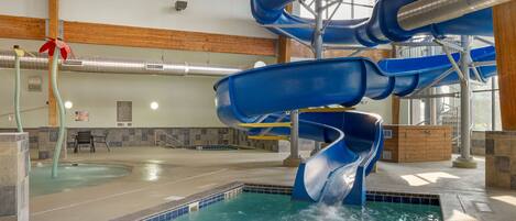 Um parque aquático interno com vários escorregadores azuis e uma área de piscina.