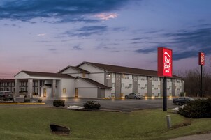 Um Red Roof Inn com um edifício de dois andares, estacionamento e um gramado bem cuidado.
