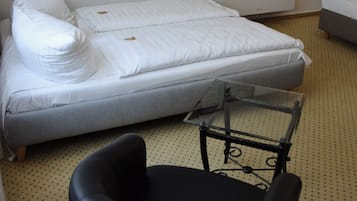 Quarto de hotel com uma cama, uma cadeira e uma parede com quadros.