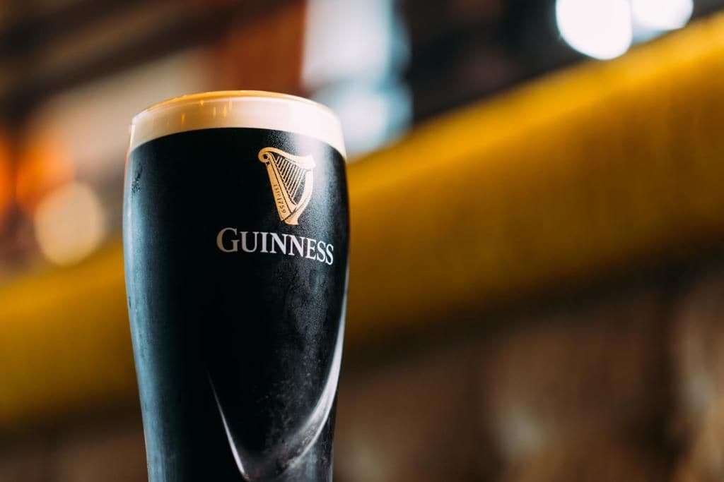 Primeiro plano de um copo de Guinness com o logotipo, sobre um fundo desfocado.