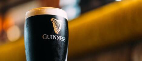 Primeiro plano de um copo de Guinness com o logotipo, sobre um fundo desfocado.