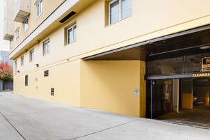 Edifício amarelo com placa indicando estacionamento para hóspedes.
