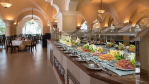 Um buffet com diversos tipos de comida e uma área de estar com mesas e cadeiras.