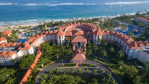 Resort com pátio central, vários edifícios com telhados vermelhos e uma praia ao fundo.