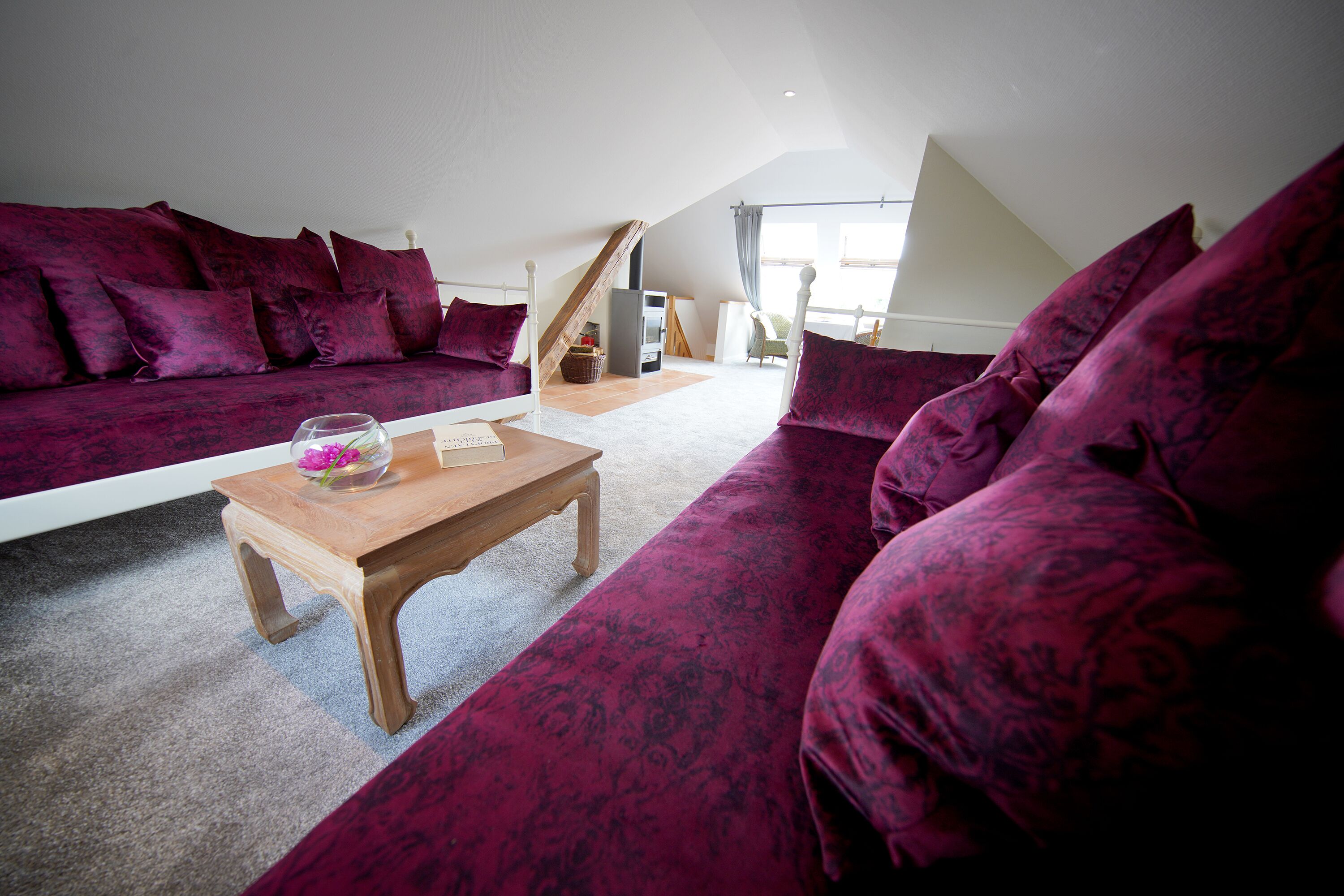 Uma sala de estar acolhedora com um sofá roxo grande, uma mesa de centro de madeira e uma lareira.