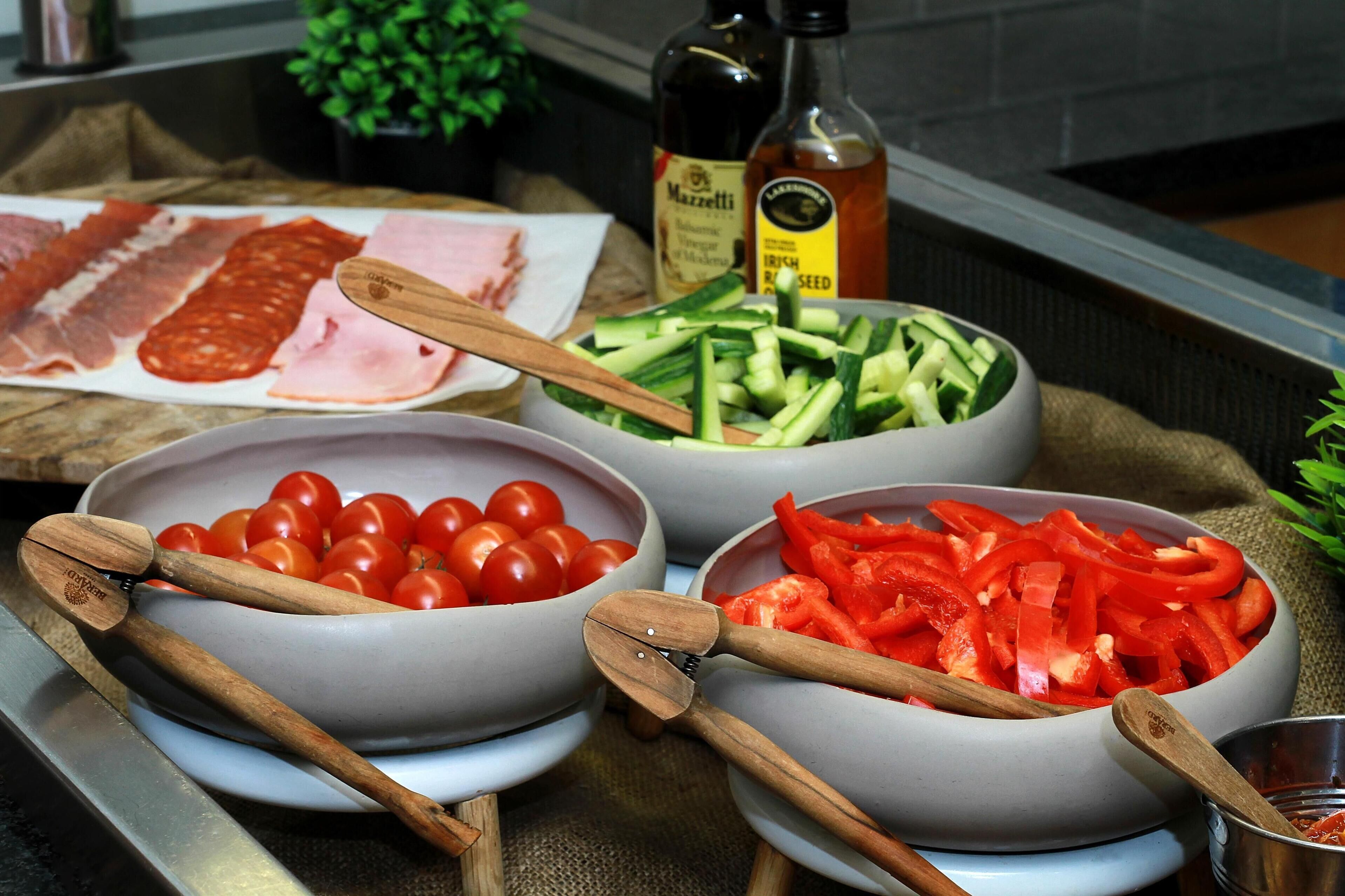 Tigelas com tomate, pepino e pimentão vermelho em uma bancada de cozinha.