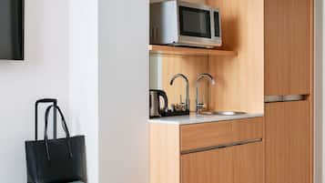 Cozinha compacta com micro-ondas, duas torneiras de aço inoxidável e uma pia.