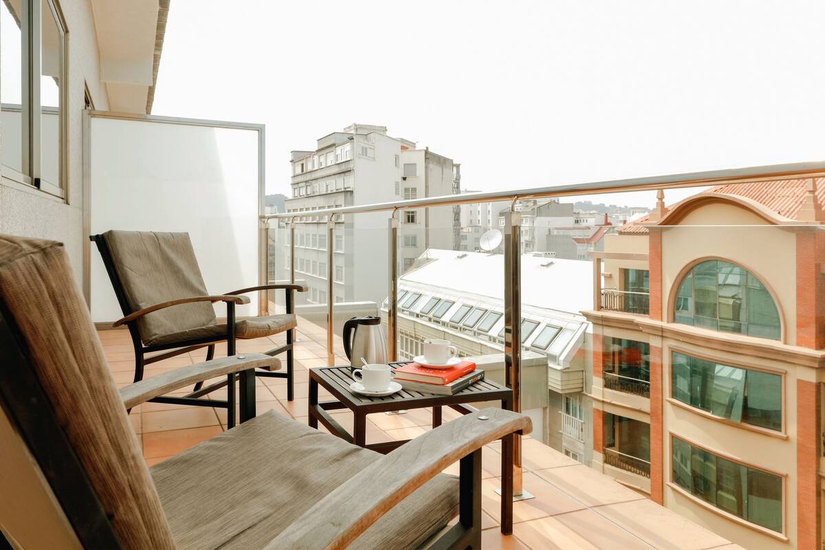 Varanda com duas cadeiras, uma mesa e vista para edifícios.