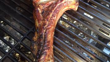 Uma grande porção de carne assando numa grelha de metal.