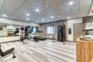 Uma academia com diversos equipamentos de exercício, uma mesa de recepção e um espelho grande na parede.