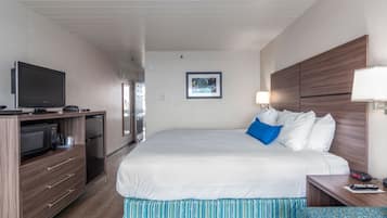 Quarto de hotel com cama, televisão, micro-ondas, mini-geladeira, escrivaninha e mesa de cabeceira.