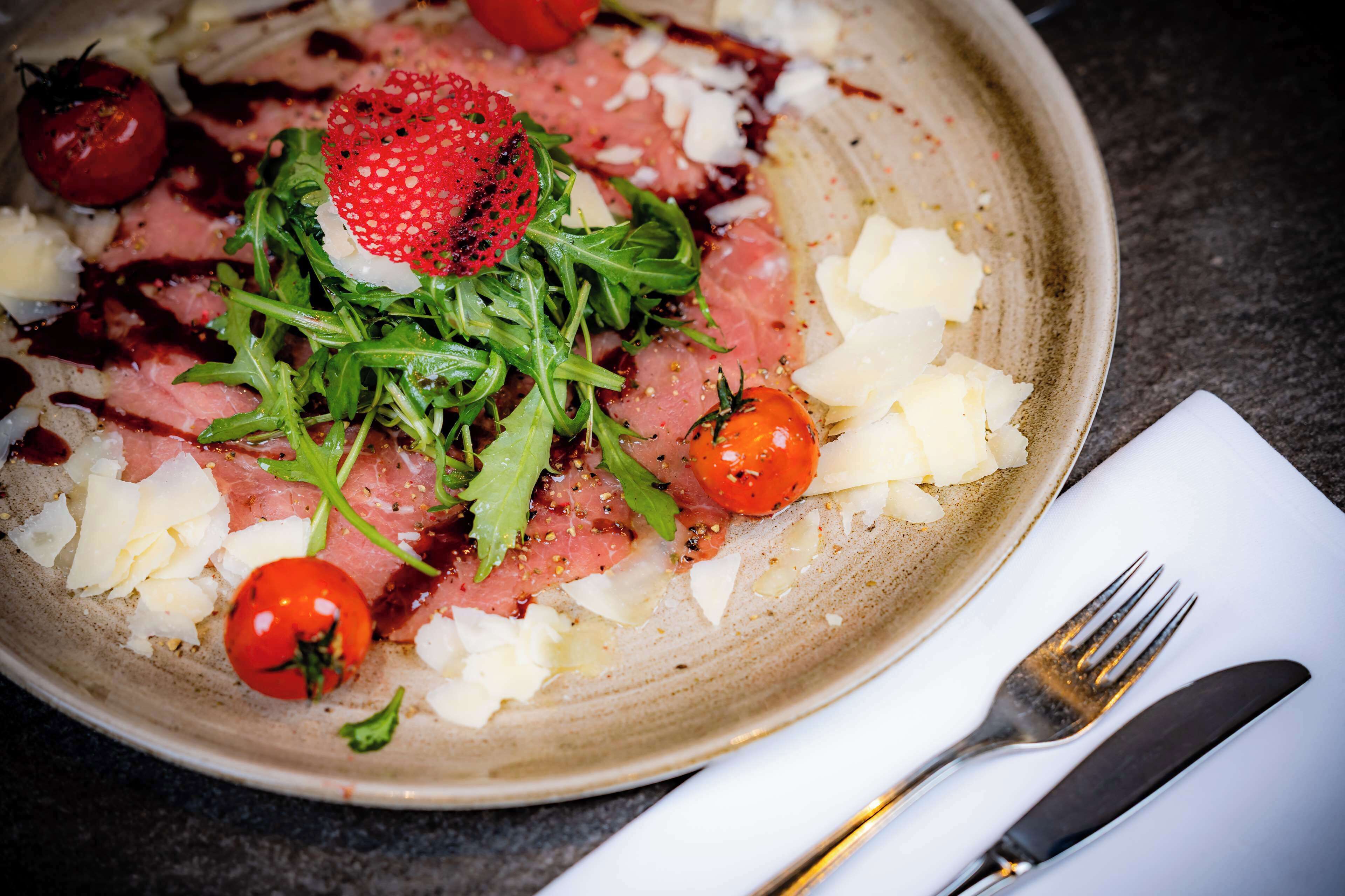 Prato de comida com rúcula, tomate cereja e queijo ralado.