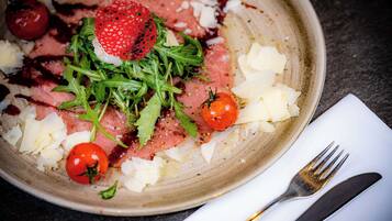 Prato de comida com rúcula, tomate cereja e queijo ralado.