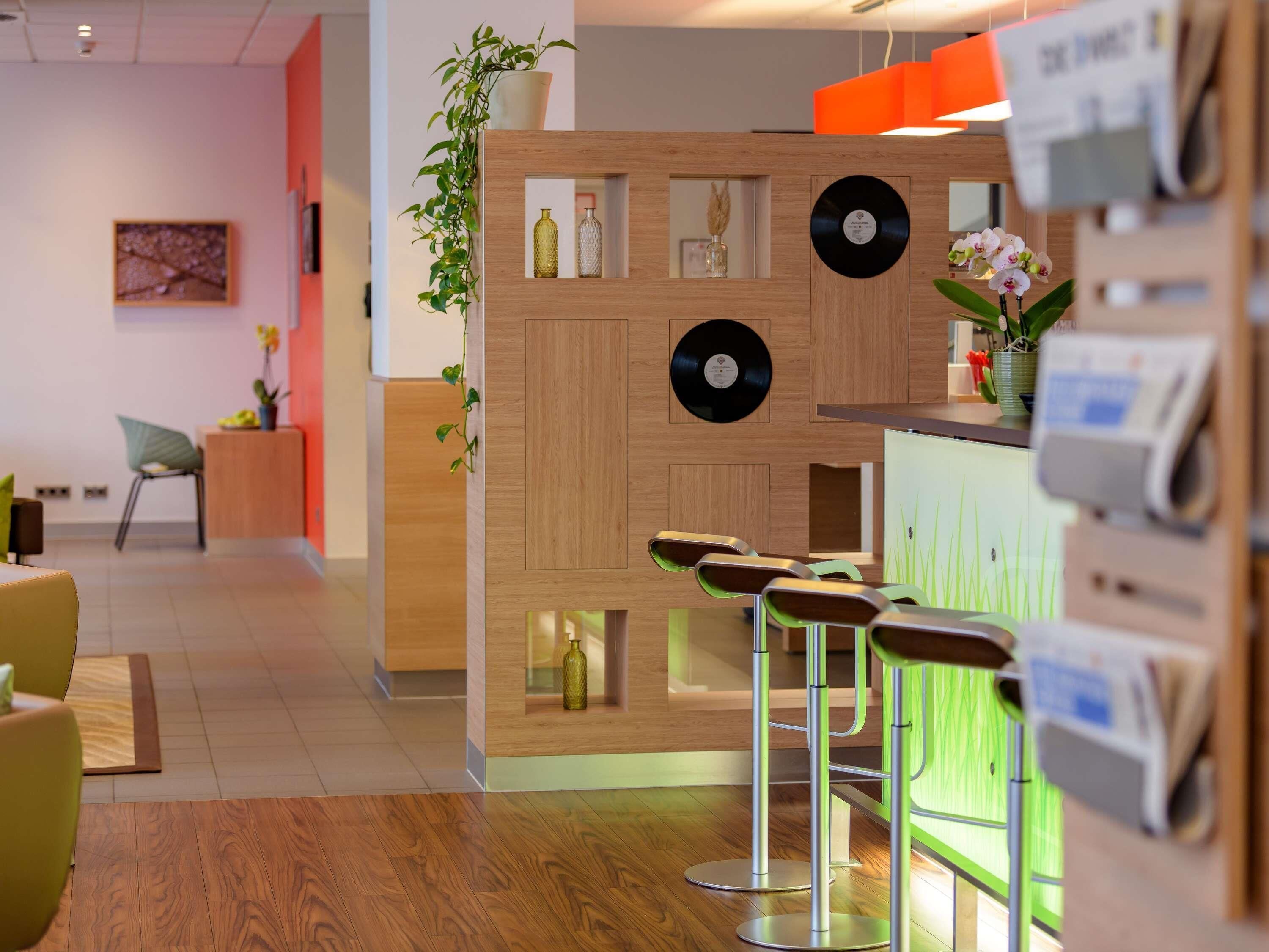 Uma área de bar moderna com detalhes em madeira, banquetas e uma planta.